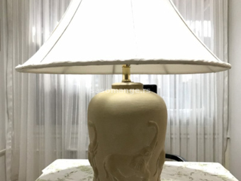 Keramička stona lampa sa reljefnim motivom slonova i belim šivenim abažurom koji se pere