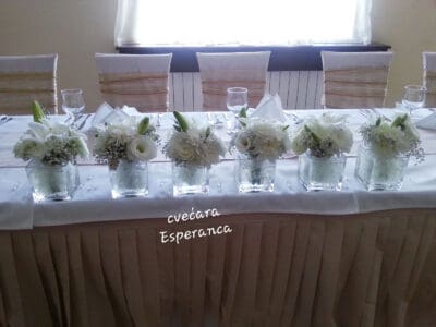 Dekoracija mladenačkog stola, staklene vaze sa buketima od ruža, ljiljana, gipsofile, lizijantusa