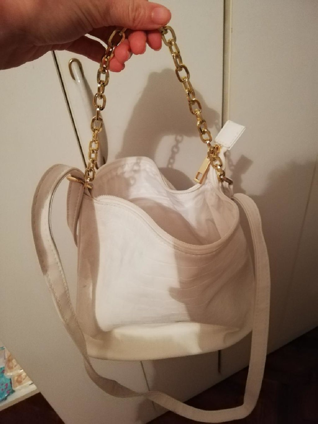 Bela torbica, manja, ima veliki kais i mali zlatni lancic koji moze da