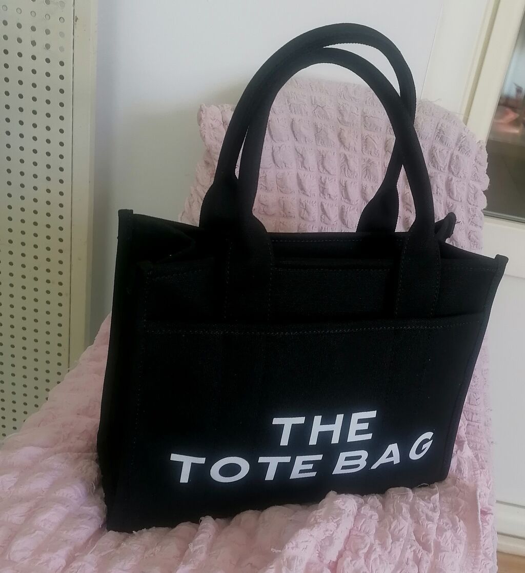 Crna platnena torba sa ručkama i natpisom "THE TOTE BAG" bele boje
