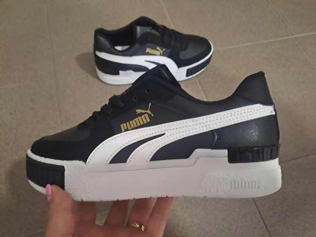 Puma ženske patike, crno‑bele boje sa zlatnim Puma logotipom. Moderna