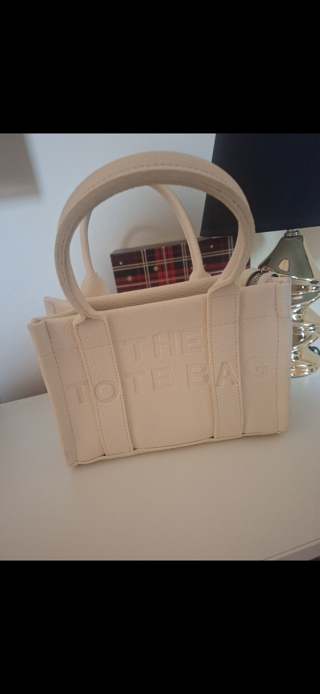 Mini tote torba u bež/ekru nijansi. Model sa utisnutim natpisom “THE