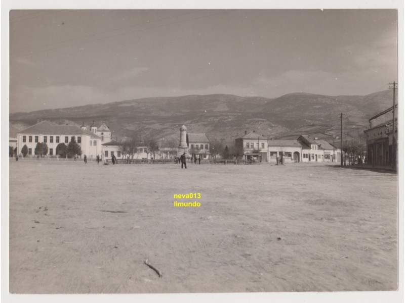 Trg sa spomenikom u sredini,zgrade i planine u pozadin