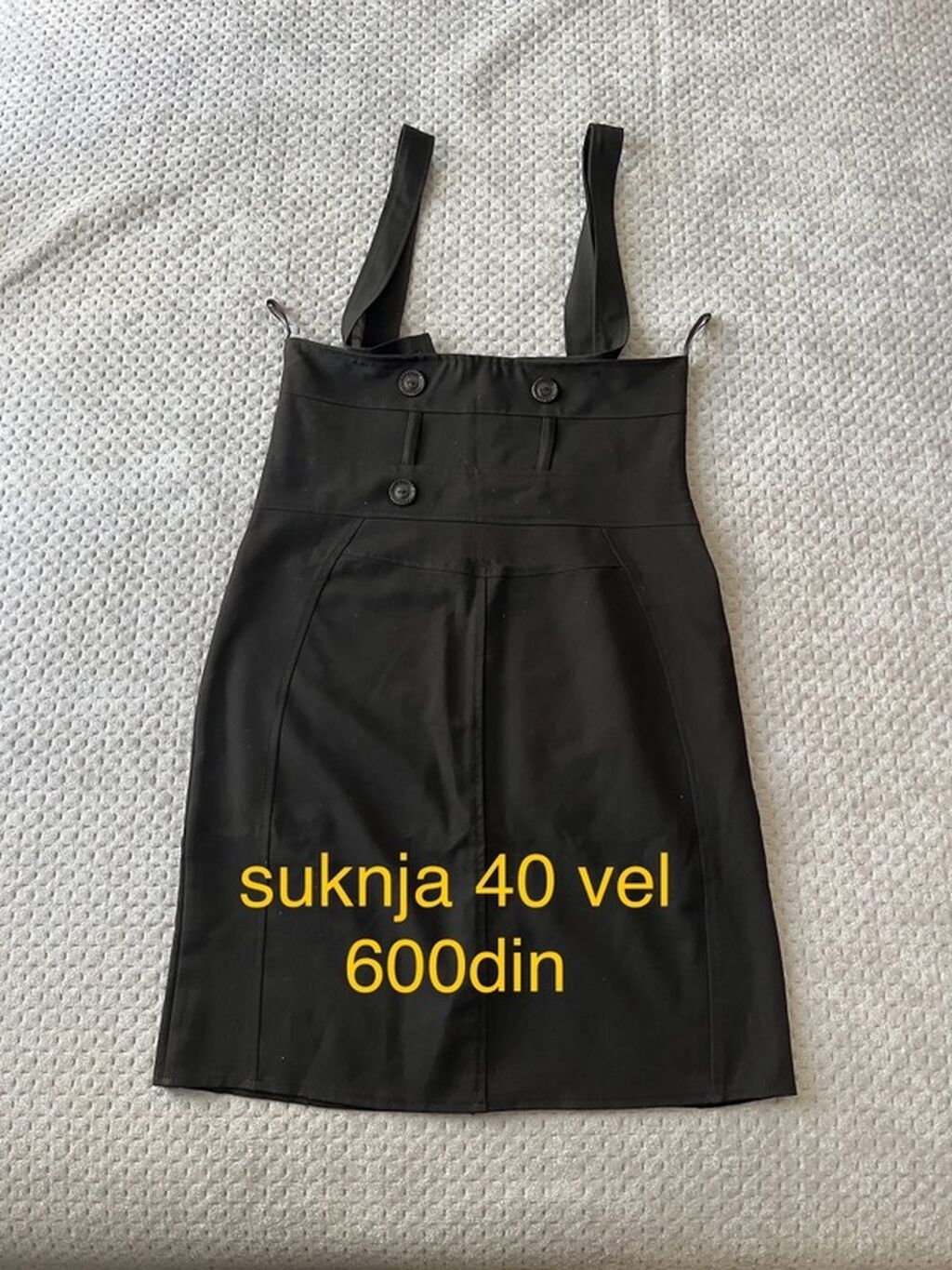 Crna suknja sa tregerima, model visokog struka. Prednji deo ukrašen sa