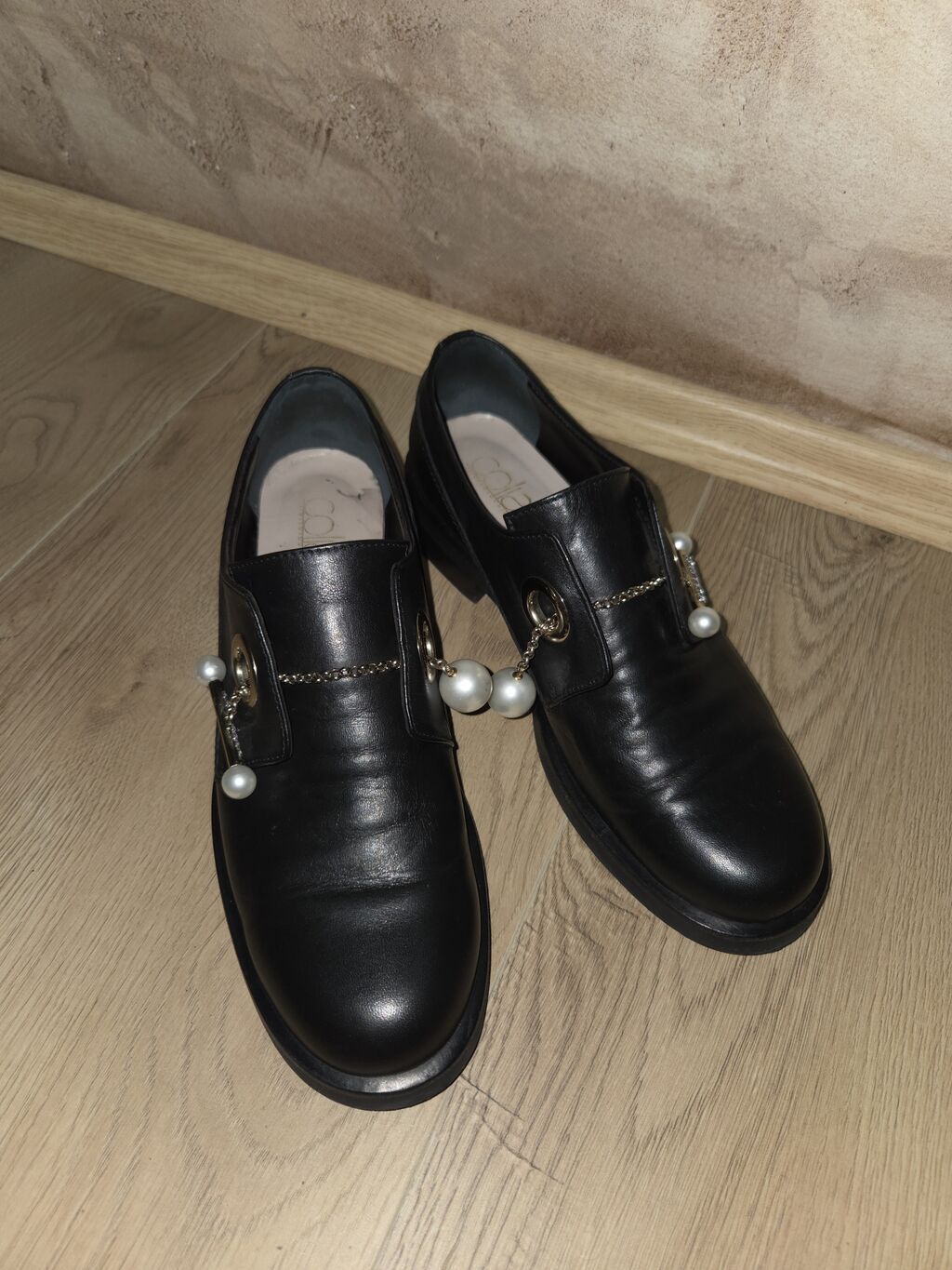 Ženske crne mokasine sa dekorativnim biserima i zlatnim detaljima. -