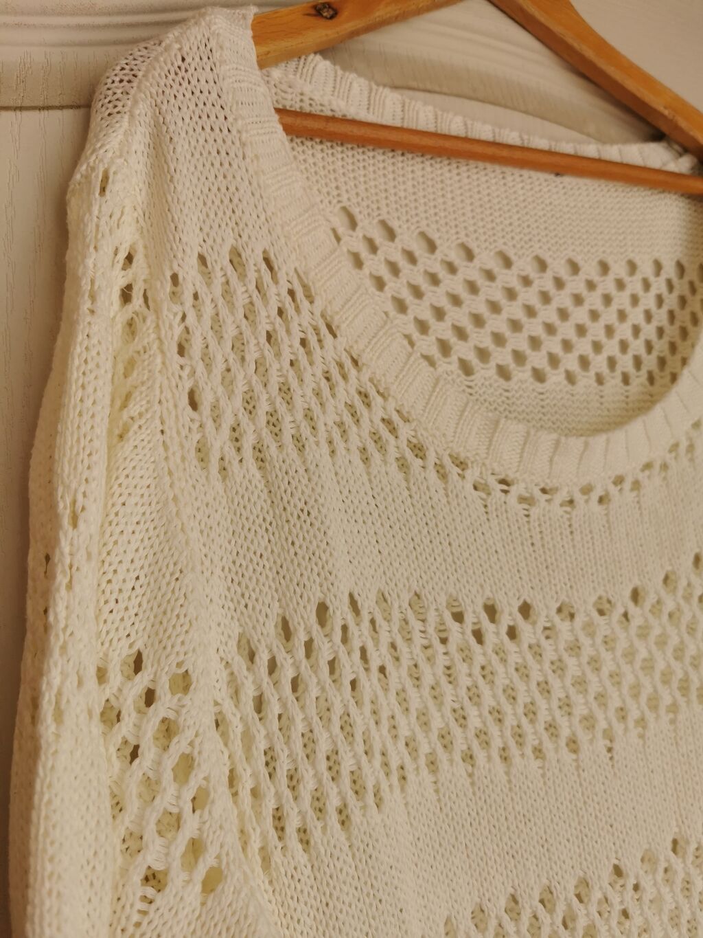 Beli pleteni džemper sa rupičastim (ažur) šarama u prugama. Širi
