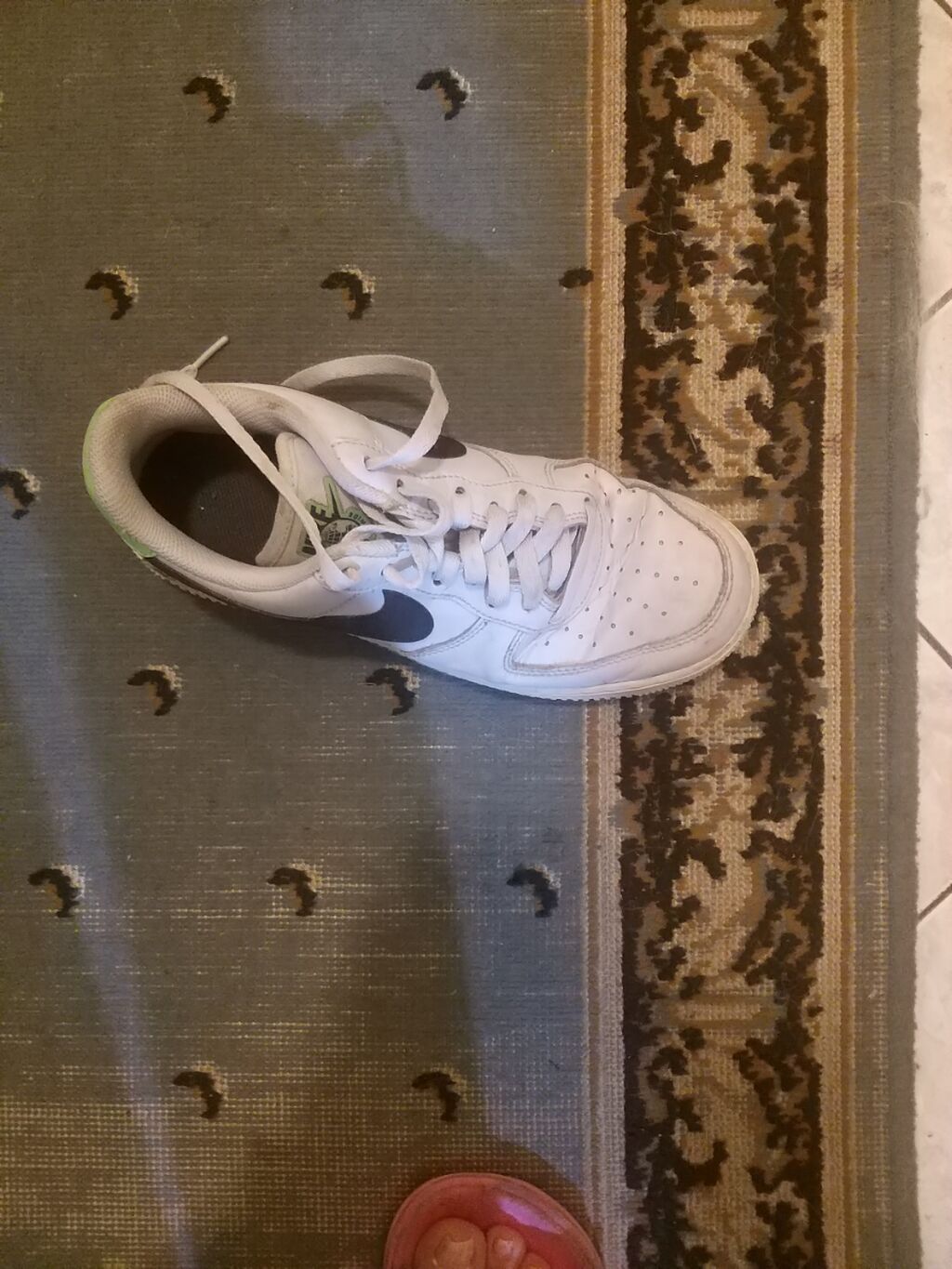 Bele sportske patike sa crnim Swoosh logotipom i zelenim detaljima na